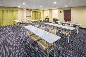 Uma sala de conferências com várias mesas e cadeiras, um relógio na parede e um sinal de saída.