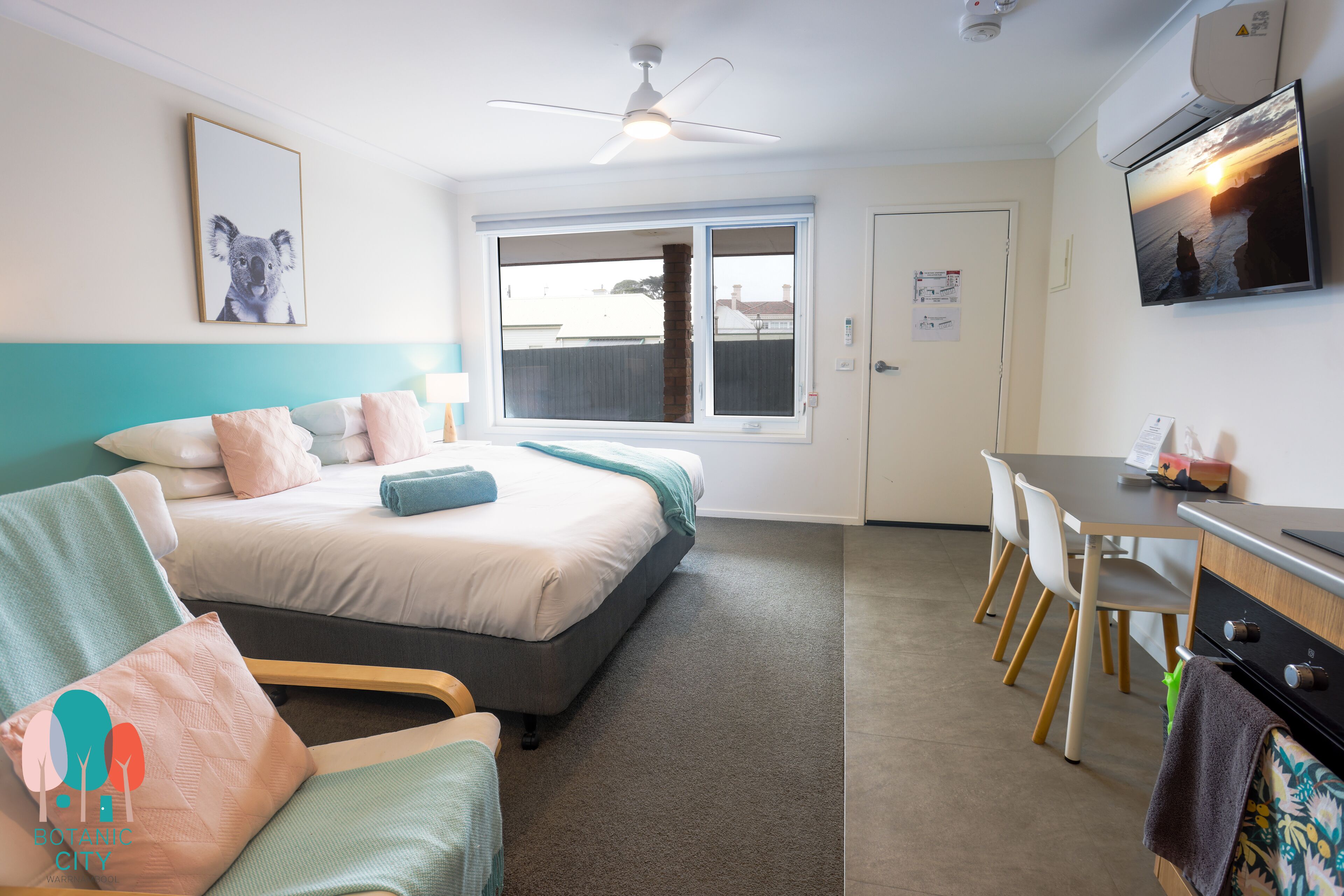 Quarto com cama, escrivaninha e cadeira. Janela com vista para edifícios.
