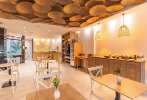 Um restaurante moderno com detalhes em palha no teto, mesas de madeira e diversas opções de assentos.