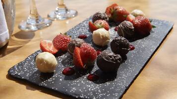 Um prato de sobremesa com morangos, chocolate e creme sobre uma lousa.