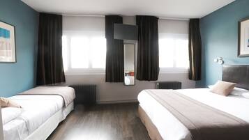 Quarto de hotel com duas camas, um espelho grande e uma janela com cortinas.