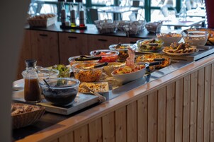 Buffet com diversos pratos e um dispensador de bebidas.