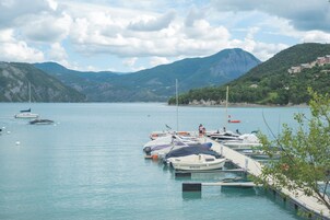 Uma marina com barcos atracados, água calma e montanhas ao fundo.