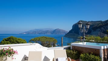 Terraço no telhado com piscina, cadeiras de descanso e vista para o mar e montanhas.