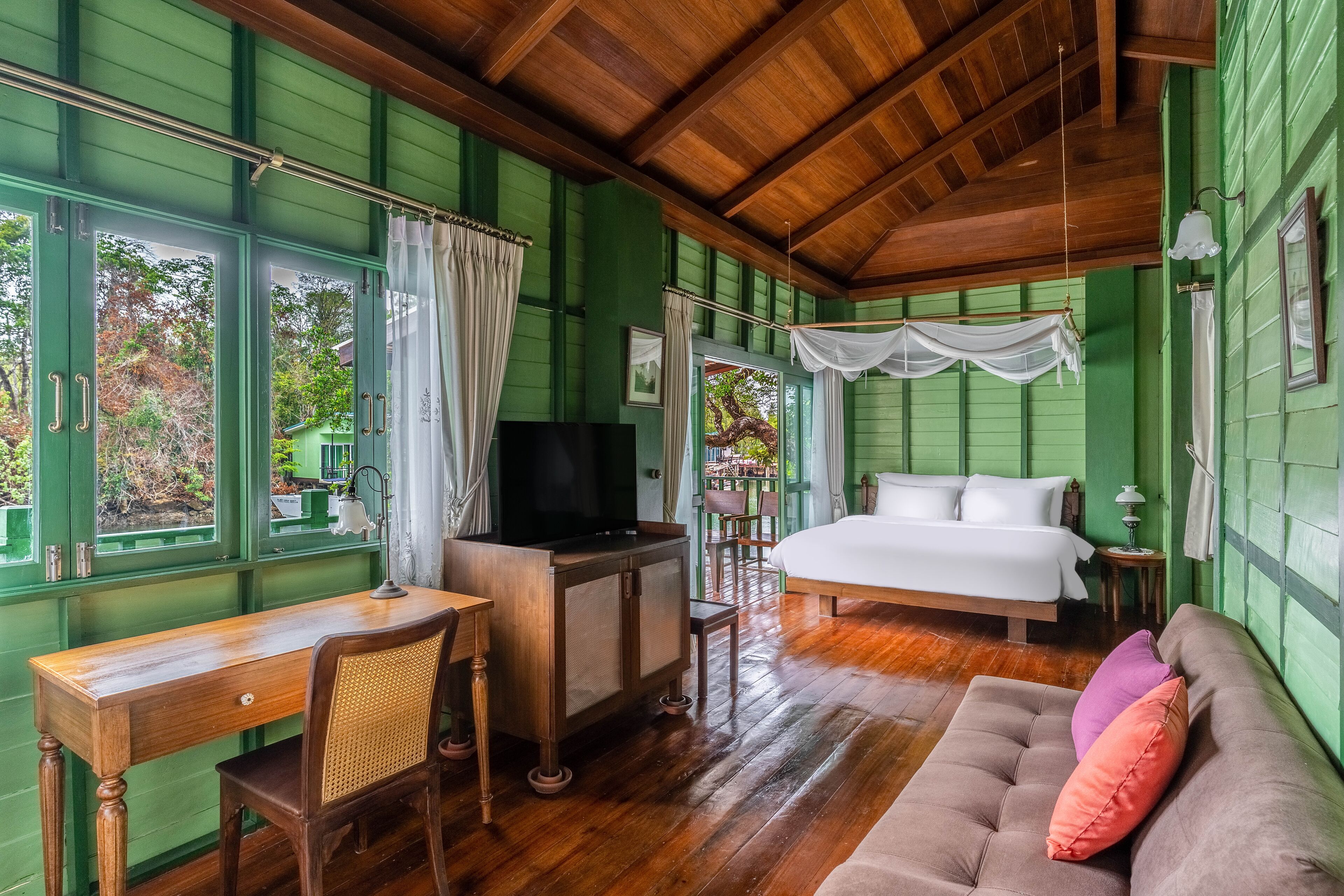 Um quarto com uma cama, uma escrivaninha, uma televisão e um sofá.