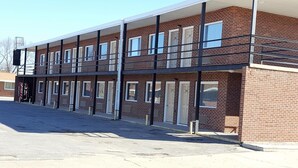 Um edifício de vários andares, feito de tijolo, com telhado plano e janelas grandes.