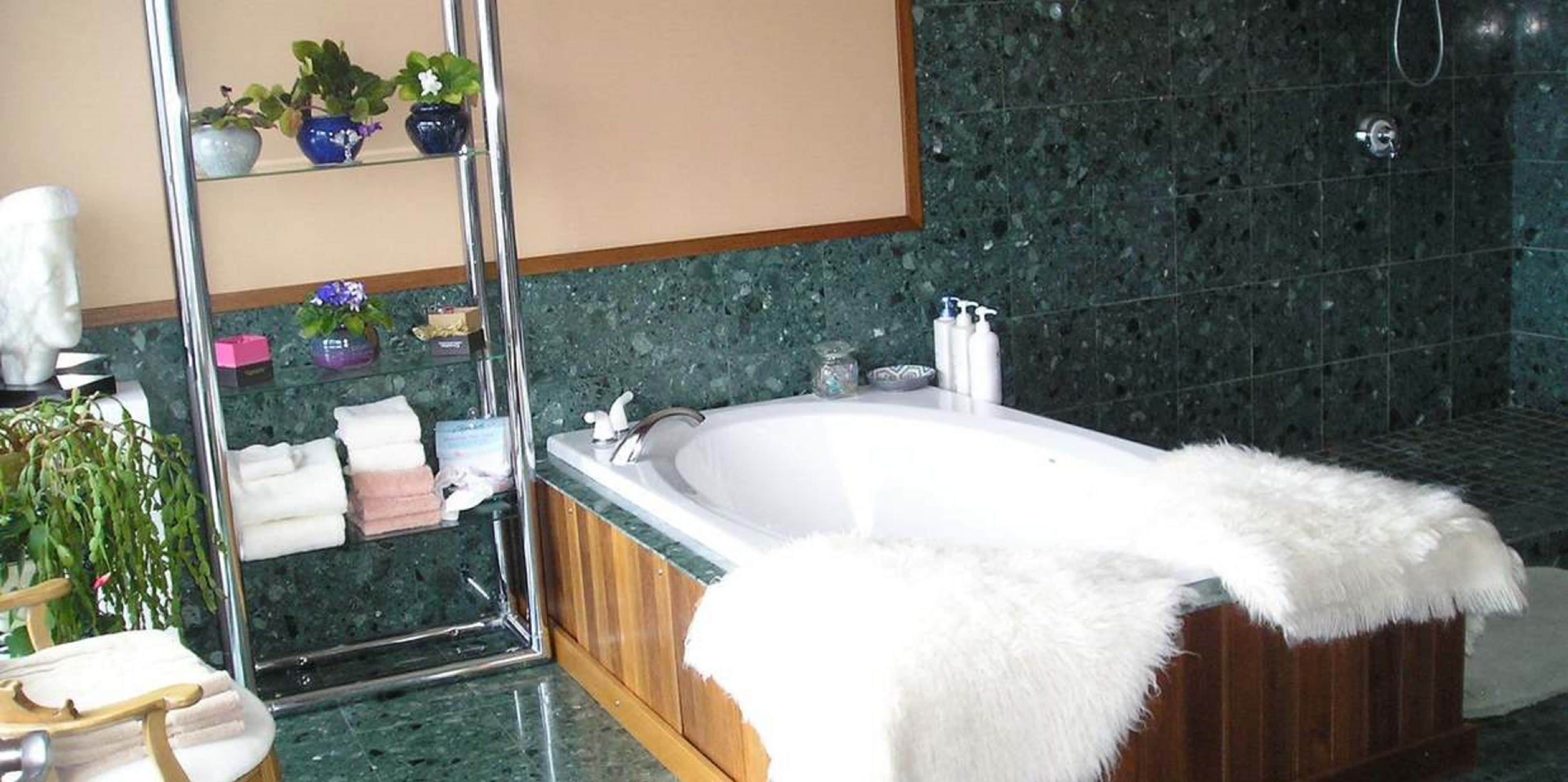 Casa de banho com banheira, espelho, um prateleira com artigos de higiene pessoal e zona de duche.