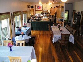 Um restaurante acolhedor com piso de madeira, um bar central e mesas com centros de mesa florais.