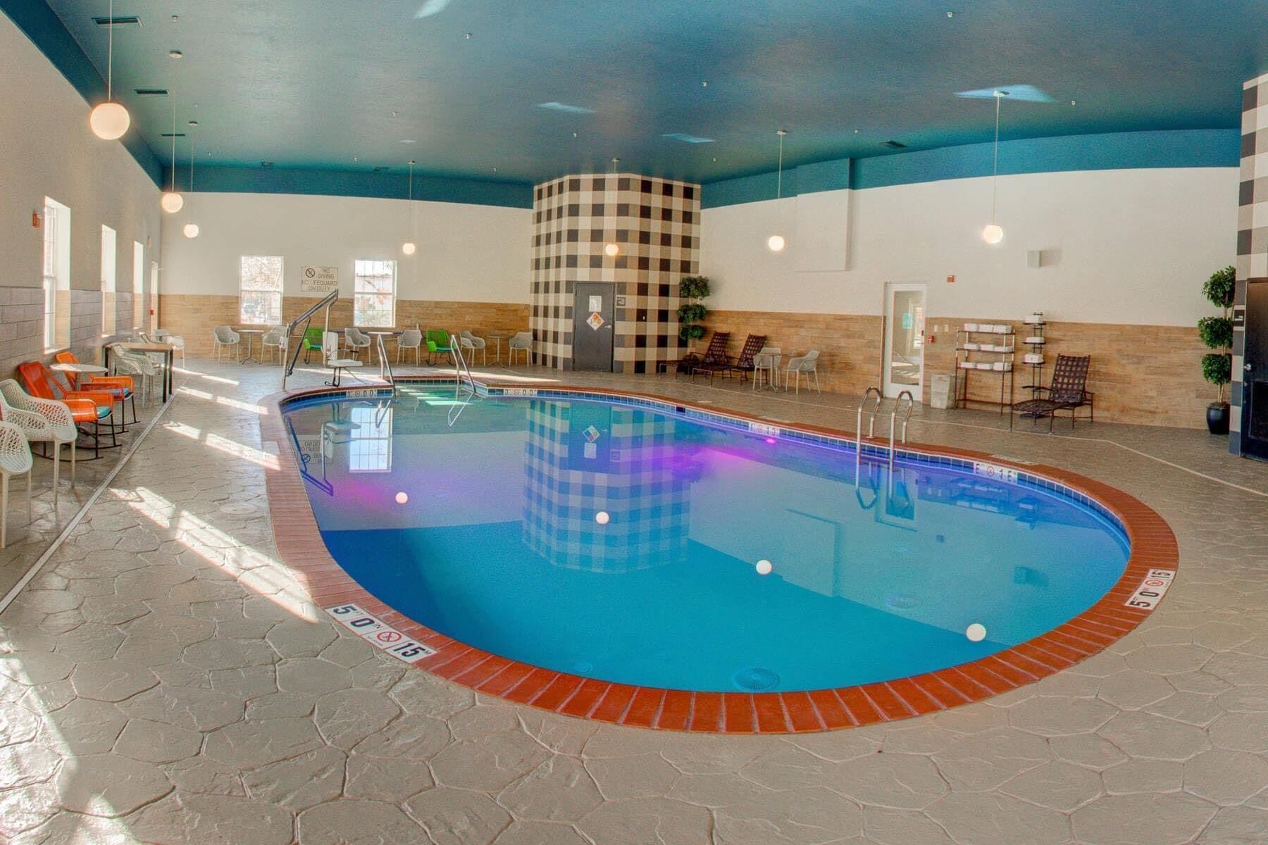 Piscina interior com parede quadriculada, área de estar e ventilador de teto.