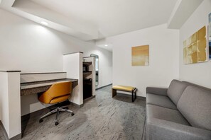 Um espaço de escritório moderno com uma mesa, cadeira e um sofá cinzento.
