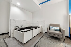 Uma casa de banho moderna com lavatório embutido, uma toalha e uma cadeira com almofada.