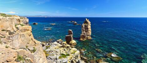 Paisagem costeira com formações rochosas e mar azul cristalino.
