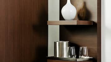 Interior moderno com um armário de madeira, uma prateleira com um vaso branco e copos, e um lustre.