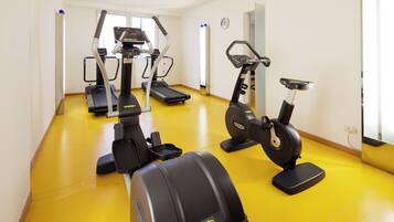 Uma sala de ginástica com bicicletas ergométricas e esteiras.