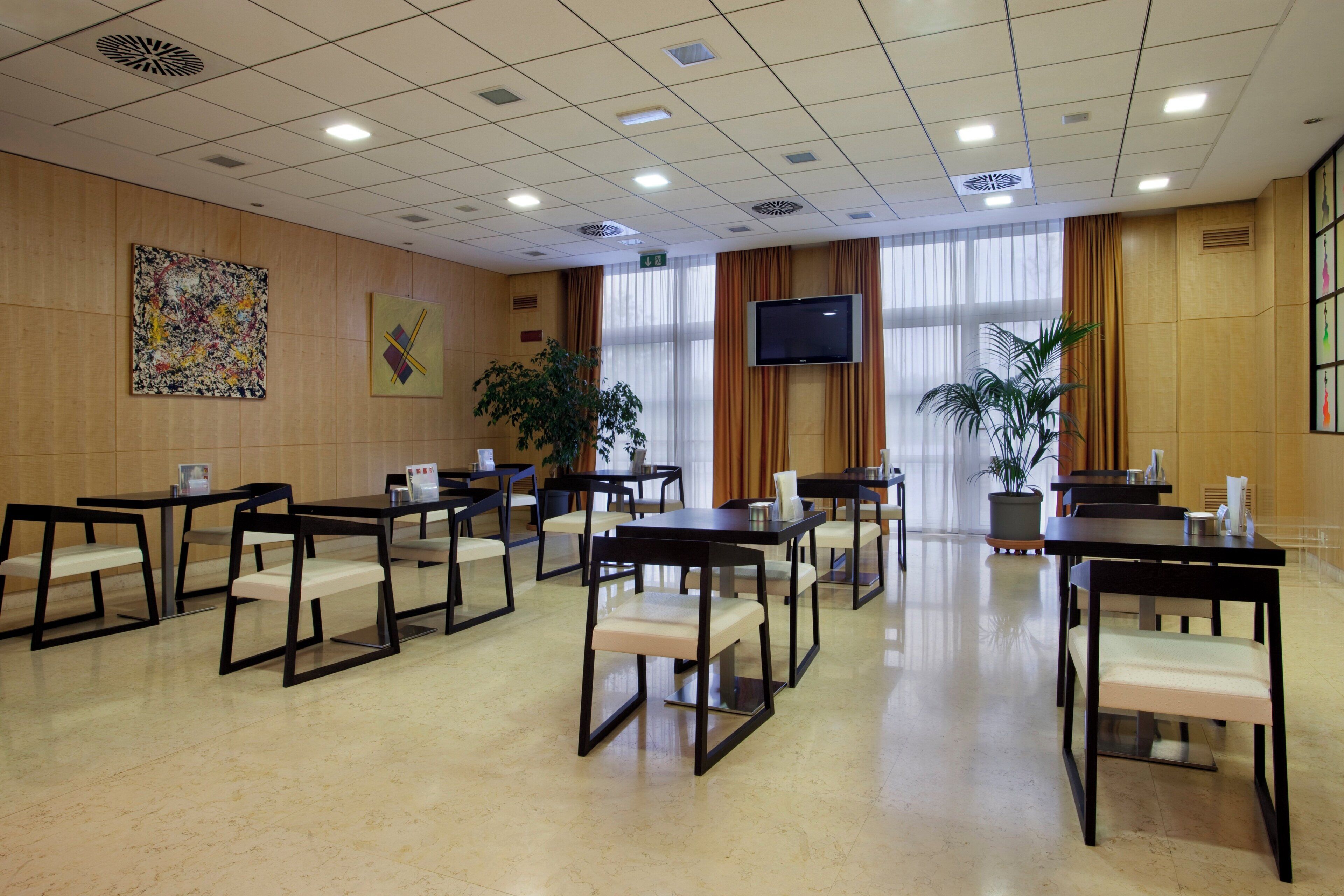 Uma sala de conferências com várias mesas e cadeiras, uma TV de tela plana e obras de arte nas paredes.