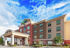 Um hotel Holiday Inn Express com entrada coberta, vários andares e céu claro.