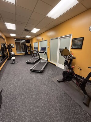 Centro de ginástica com esteiras, bicicleta ergométrica e aparelhos de musculação.