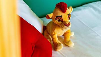 Um brinquedo de pelúcia numa cama com um travesseiro branco e um travesseiro vermelho.