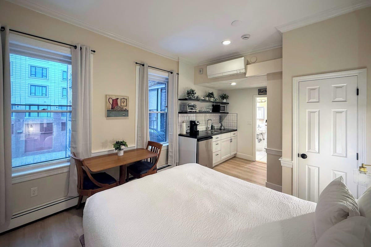 Quarto com cama, escrivaninha e vista para o exterior.