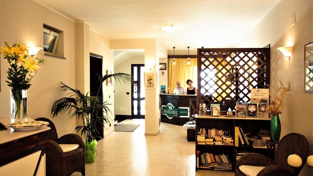 Uma área de recepção de hotel com balcão, espaço de estar e um balcão de atendimento.