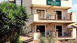Hotel Marabel de dois andares, com varandas, plantas em vasos e céu claro.