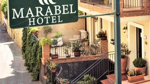 Placa do Hotel Marabel com uma escadaria que leva a uma varanda com plantas em vasos.