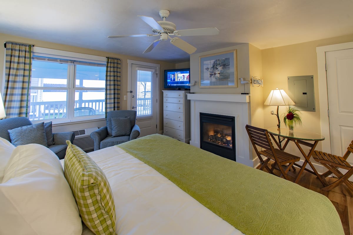 Quarto de hotel com cama, lareira, televisão e varanda com vista.