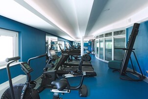 Uma academia com equipamentos de cardio, uma bicicleta vertical e um remo.