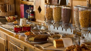 Um buffet com diversas opções de comida, incluindo frutas, cereais e doces.