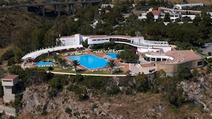 Um resort com várias piscinas, incluindo uma grande piscina central, e uma ponte ao fundo.