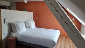 Um quarto com uma cama, mesa de cabeceira, abajur e janela.