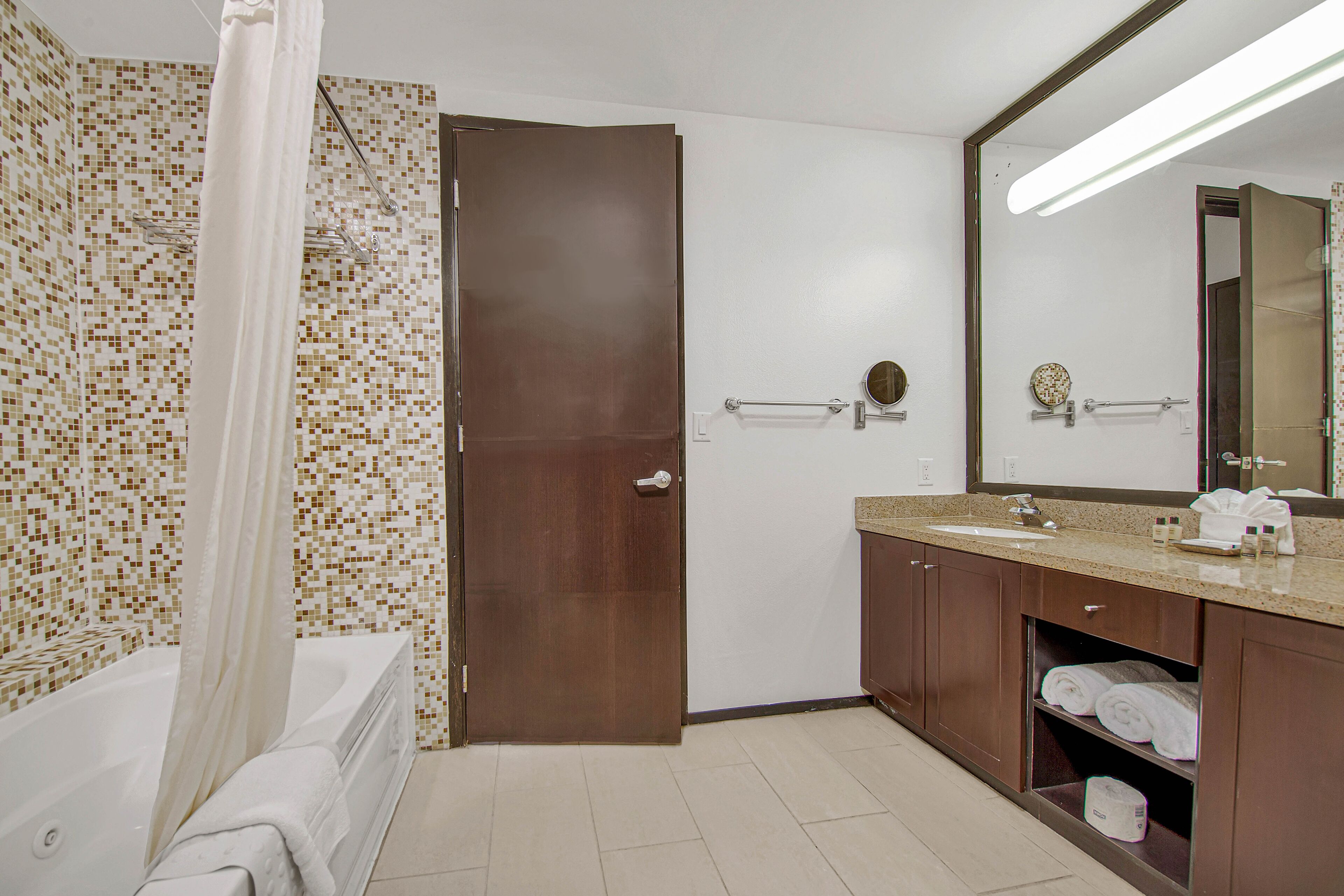 Casa de banho com cortina de chuveiro, banheira, pia e espelho.