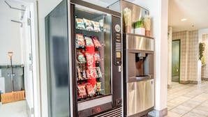 Máquina de vendas com lanches e dispensador de água no saguão de um hotel.