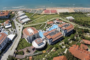 Vista aérea de um resort com vários edifícios, piscina e área de praia.