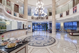 Um hall espaçoso com um lustre imponente, uma área de recepção e um buffet com diversas opções de comida.