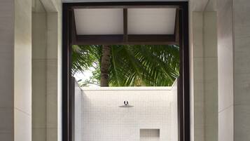 Um banheiro moderno com área de chuveiro em azulejo, porta-toalhas e um vaso de plantas.