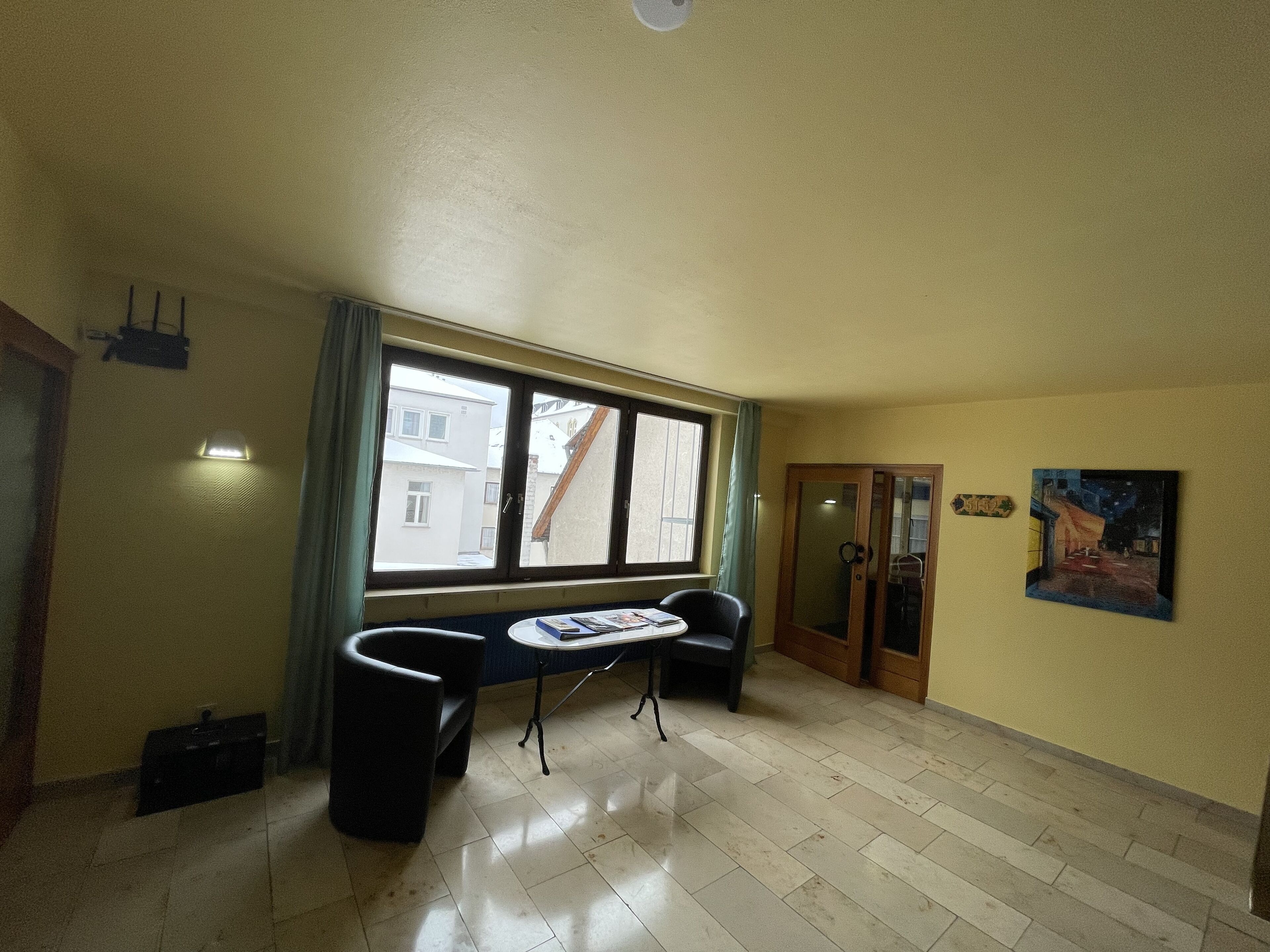 Um quarto com uma janela grande, uma mesa e uma porta.