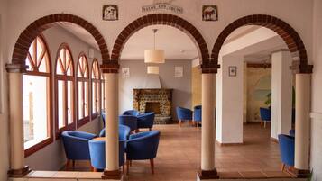 Um hall com cadeiras azuis, lareira e arcos.