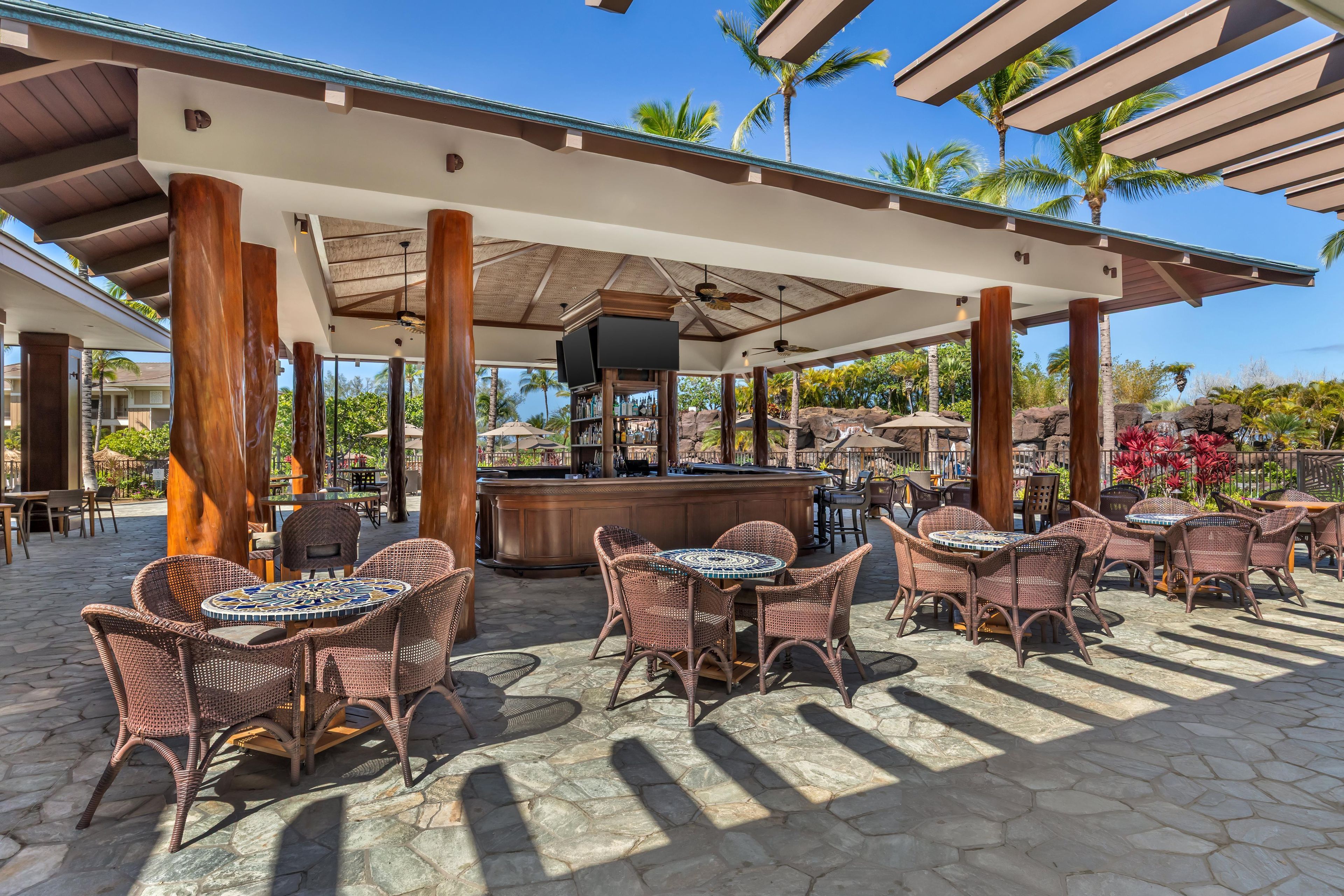 Área de bar ao ar livre com móveis de vime e piso de ladrilho.