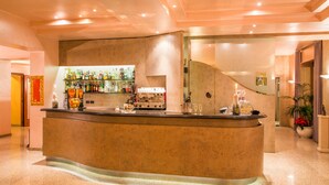 Uma área de bar com balcão curvo, prateleiras com garrafas e uma máquina de café.