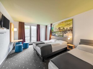 Quarto de hotel com duas camas, televisão, pintura de paisagem urbana e janela com cortinas.