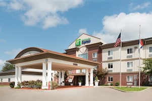 Edifício Holiday Inn Express com entrada coberta, uma bandeira e céu claro.