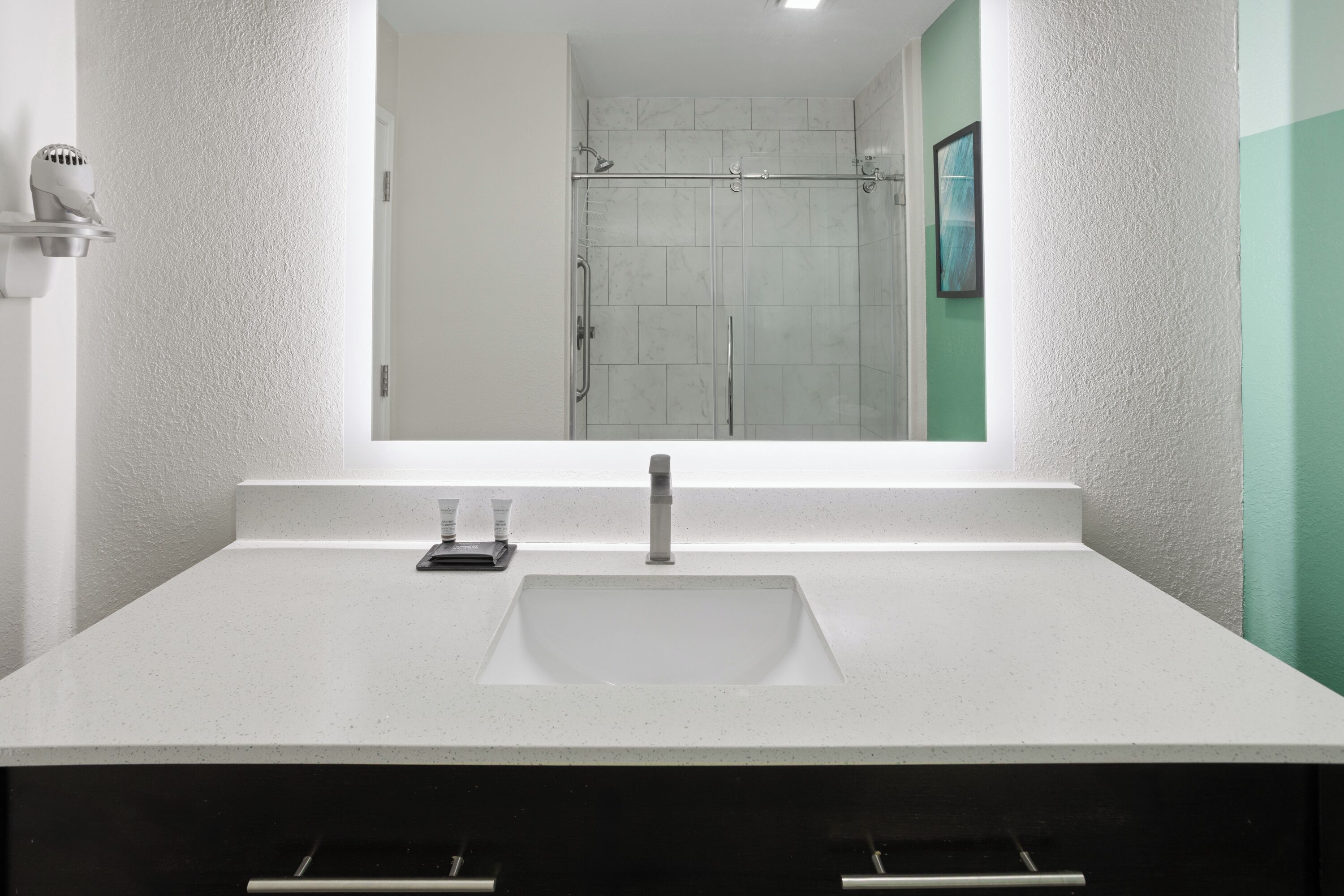 Casa de banho com lavatório branco, espelho e zona de duche.