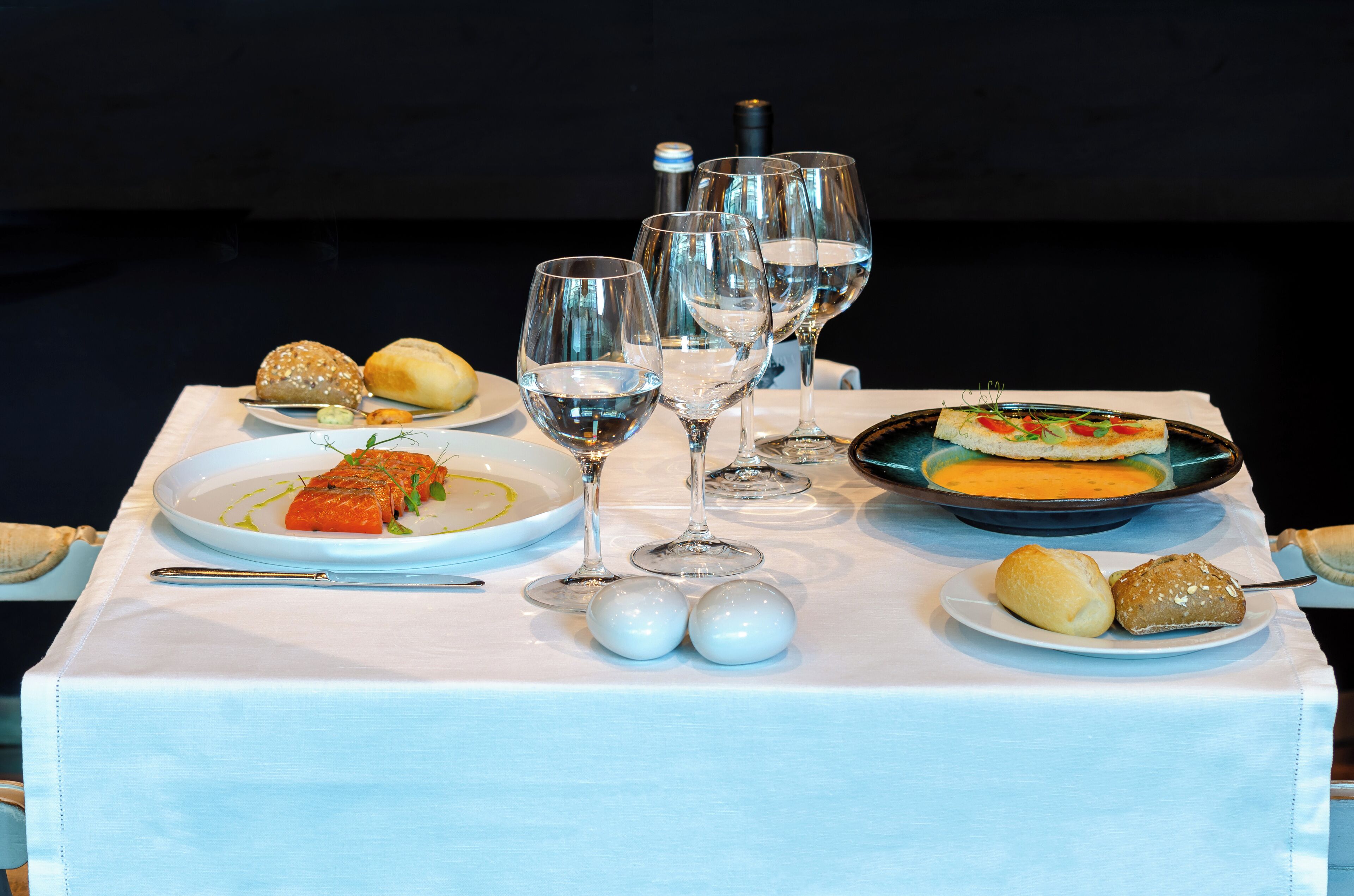 Uma mesa posta com pratos de comida, copos de vinho e uma garrafa.