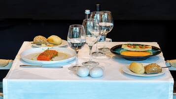Uma mesa posta com pratos de comida, copos de vinho e uma garrafa.