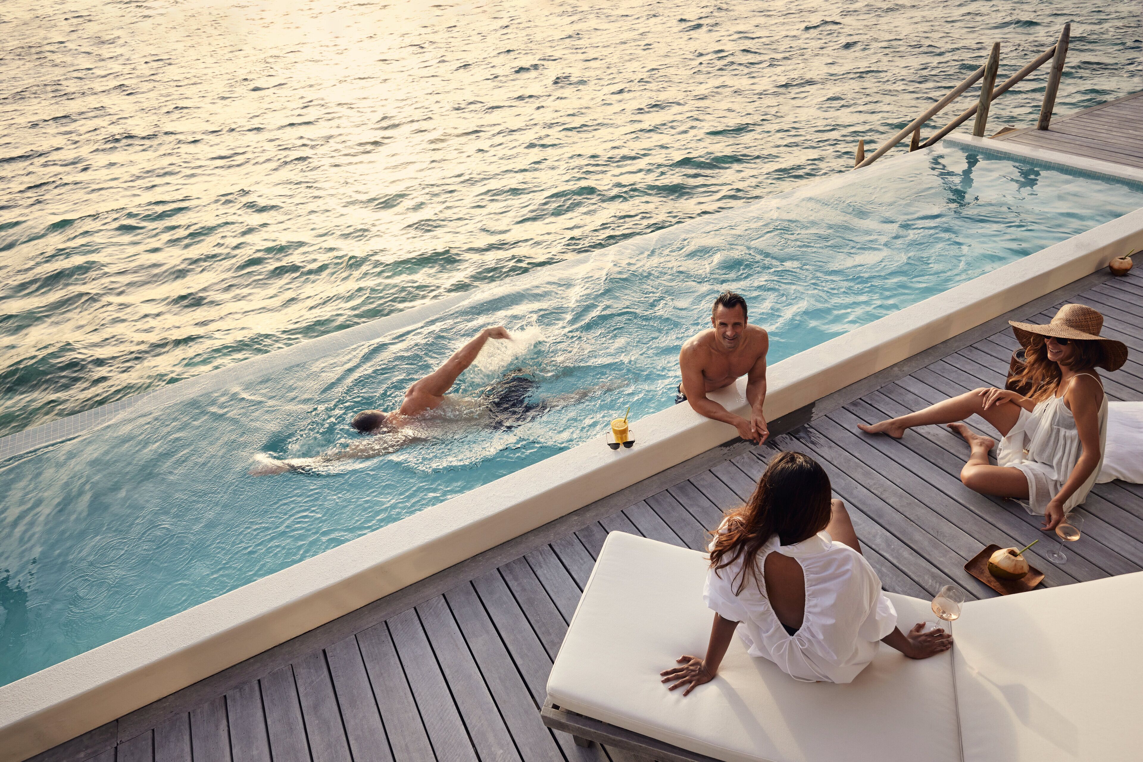 Uma área de piscina com hidromassagem, espreguiçadeiras e um deck de madeira.