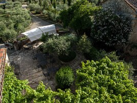 Área de pátio com piso de pedra, móveis de exterior e uma estrutura de tenda branca.