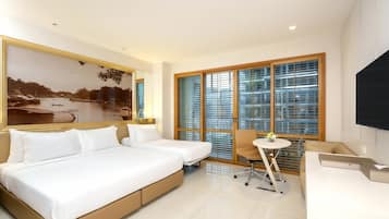 Quarto de hotel moderno com cama grande, escrivaninha, cadeira e televisão.