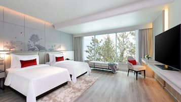 Quarto de hotel moderno com duas camas, uma janela grande, televisão de tela plana e um sofá.