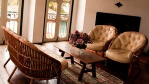 Quarto com mobiliário de vime, mesa de centro de madeira e um vaso de flores.